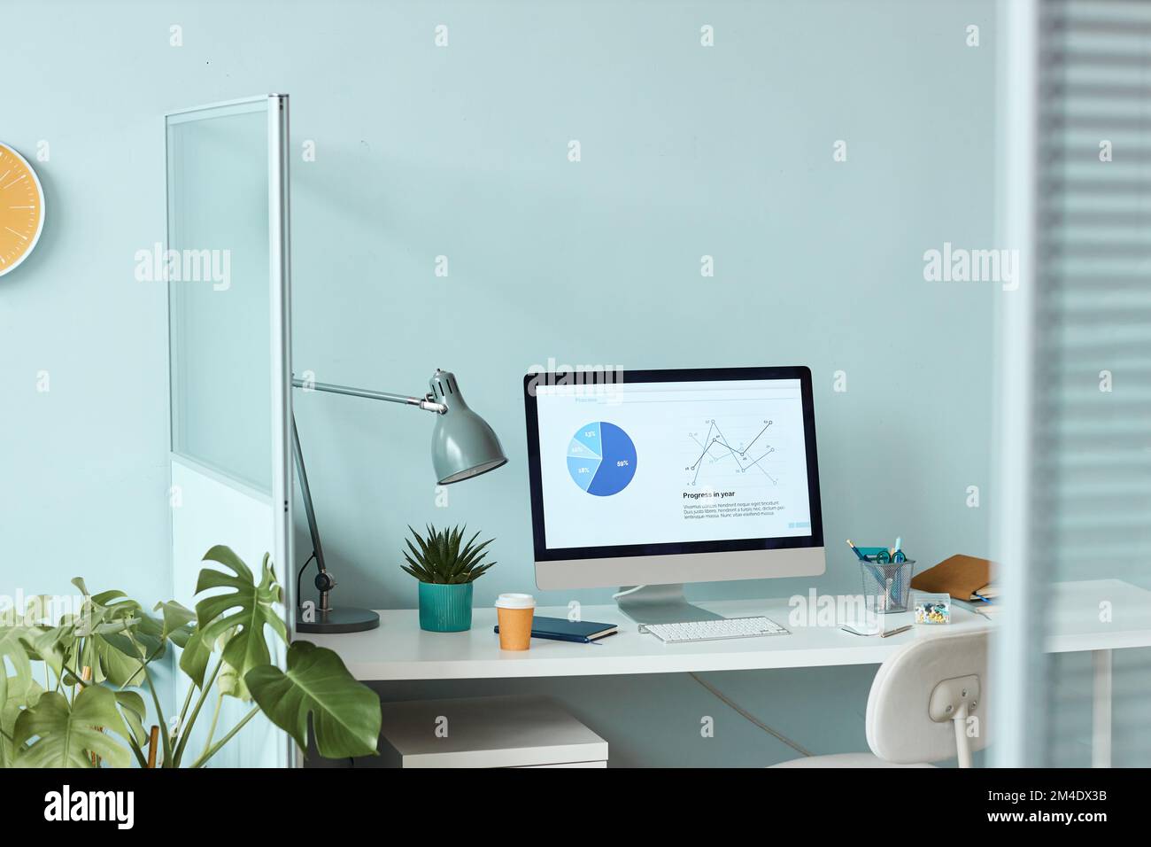 Minimal office workplace with light blue wall and statistics graphs on ...
