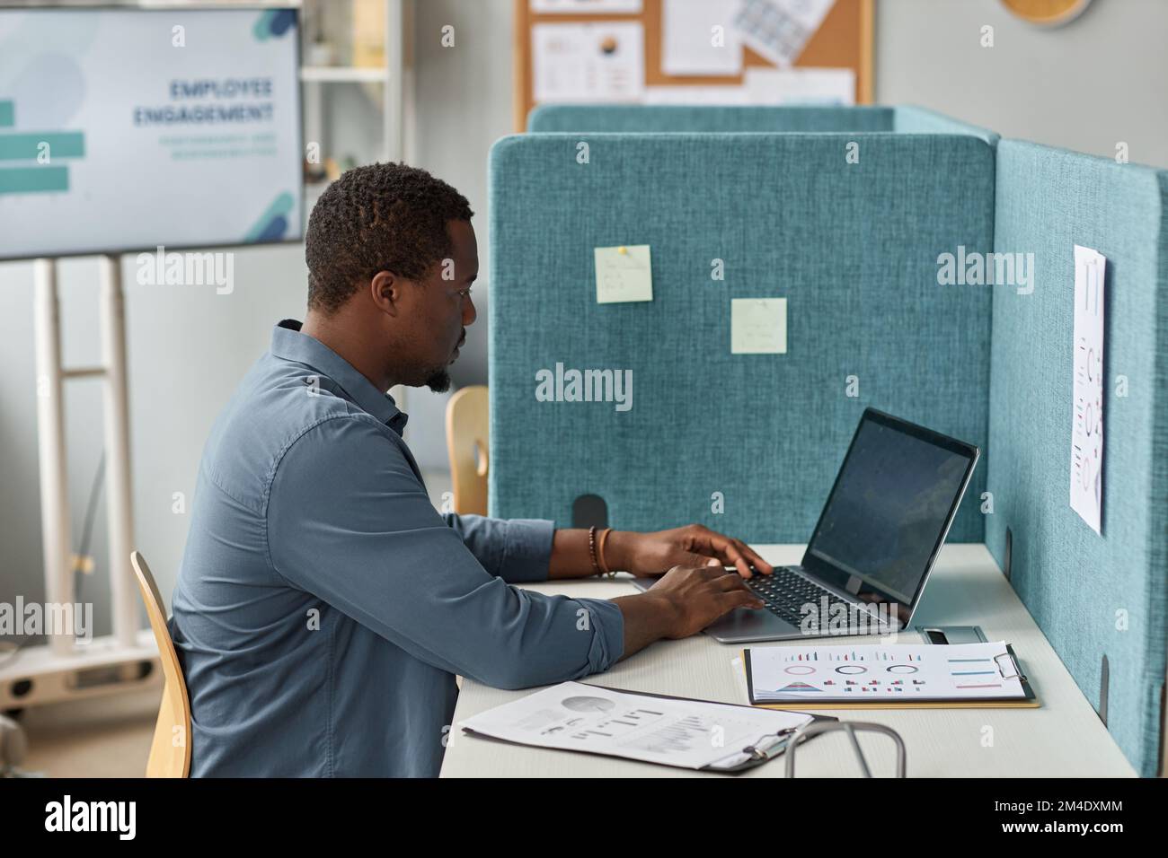Side view portrait of black man working with laptop at workplace cubicle in office Stock Photo ...