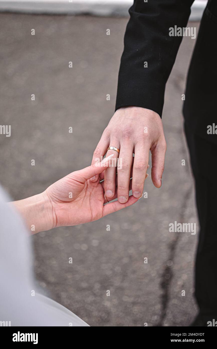 A vertical shot of the hands of the bride and groom with wedding rings ...