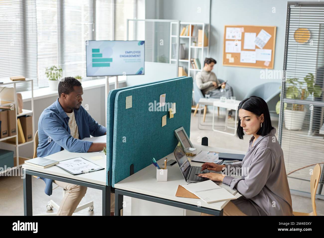 Side view portrait of two people working in office separated by ...