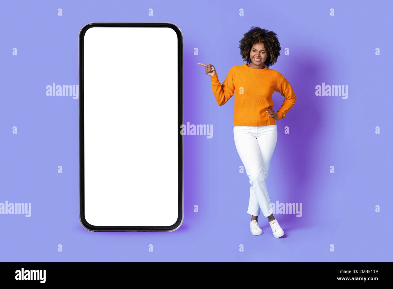 Cheerful black young woman posing by huge cell phone, mockup Stock ...