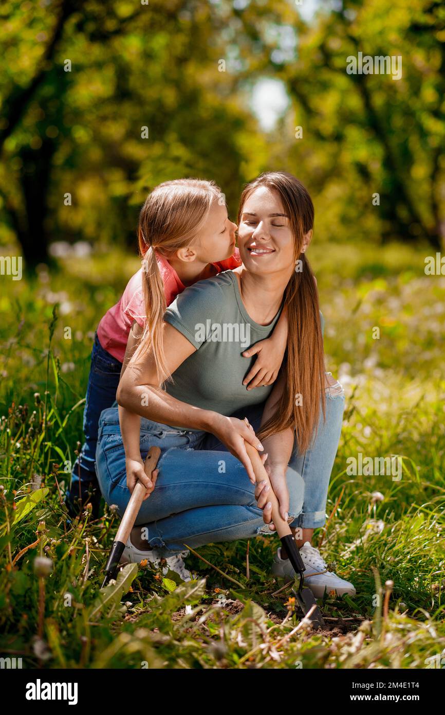 Cute woman and a blonde girl spending time in the garden and doing ...