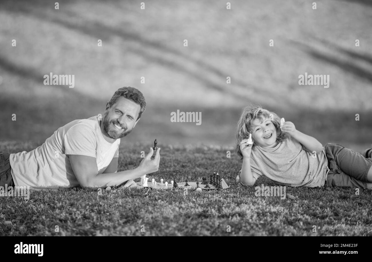 dad and kid play logic game. father and son playing chess on grass in ...