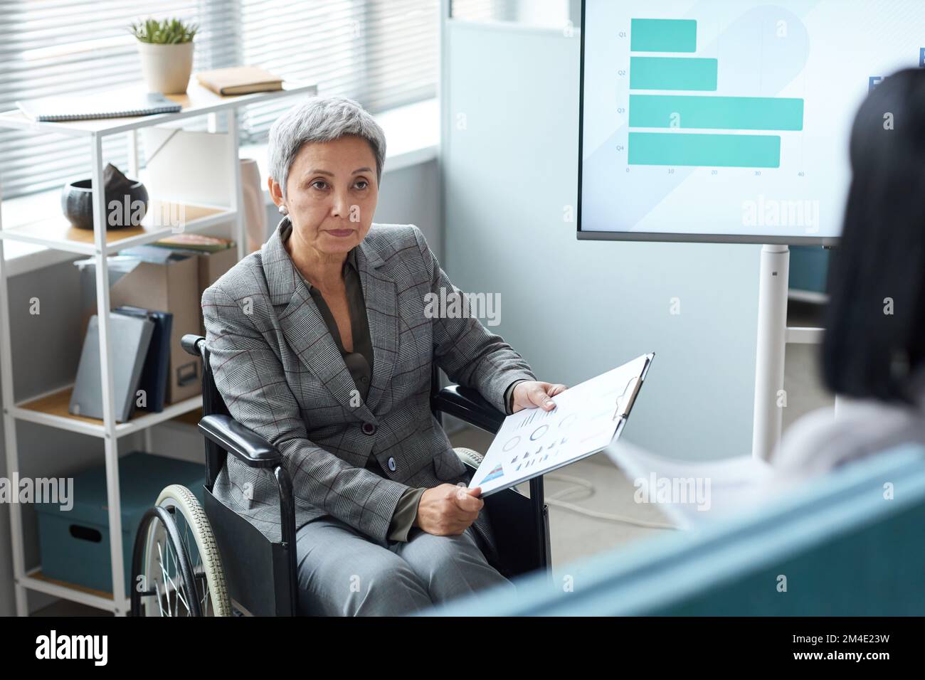 Portrait of senior female boss using wheelchair in office during ...