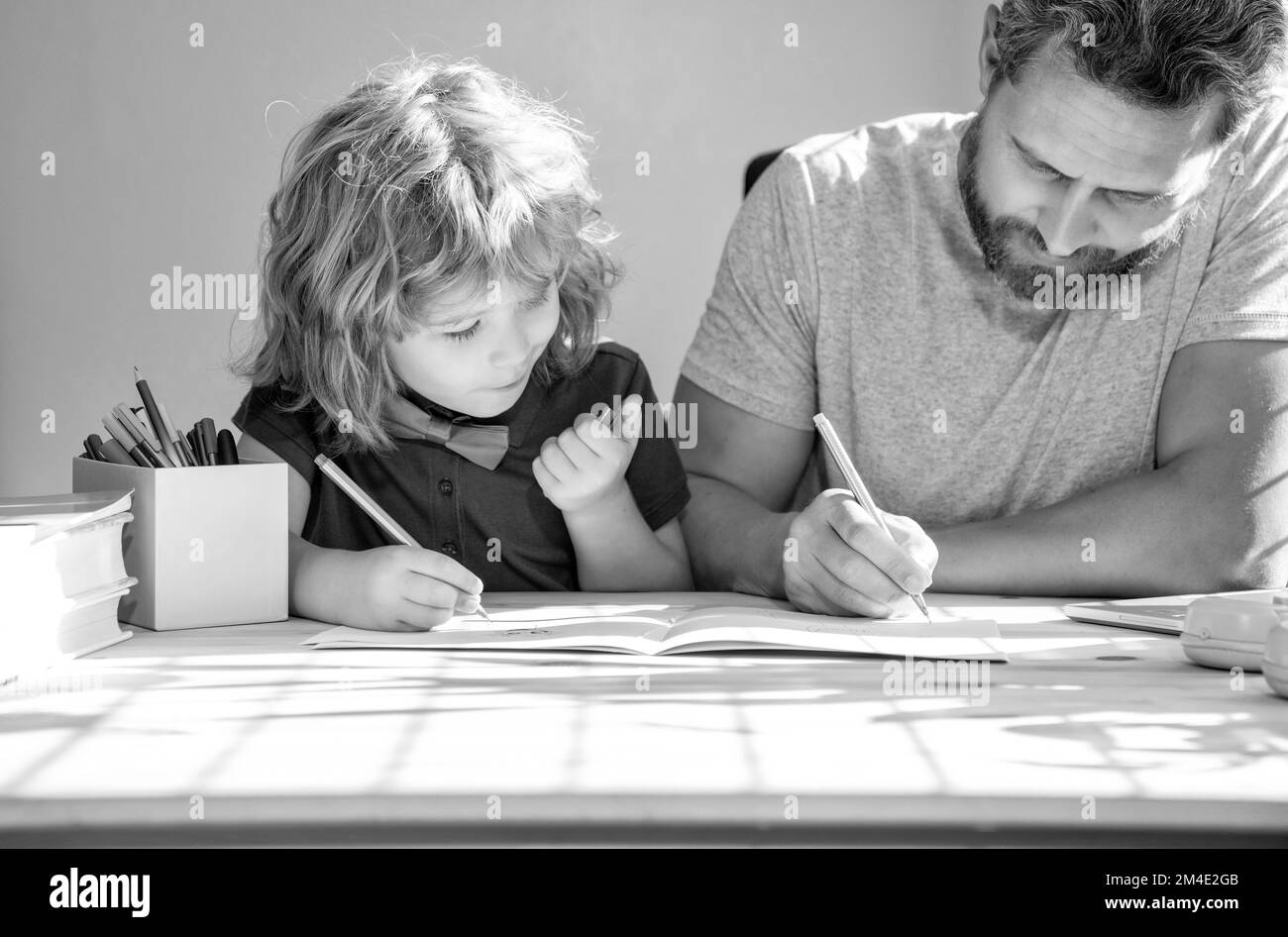 bearded father writing school homework with his child son in classroom ...