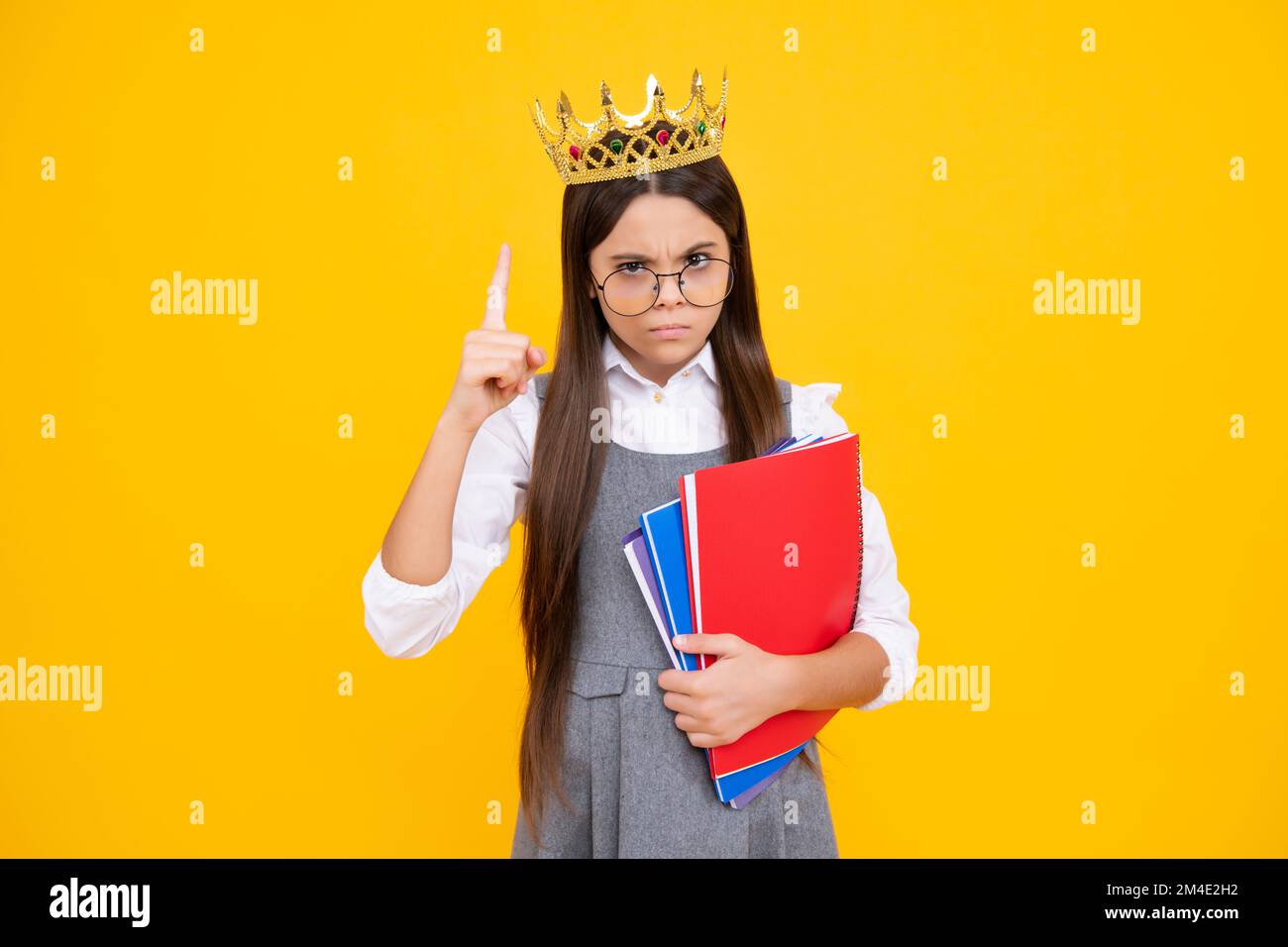 Schoolgirl in school uniform and crown celebrating victory on yellow ...