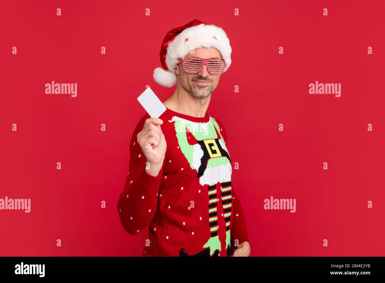 Man with party glasses in holiday sweater and Santa hat on studio ...