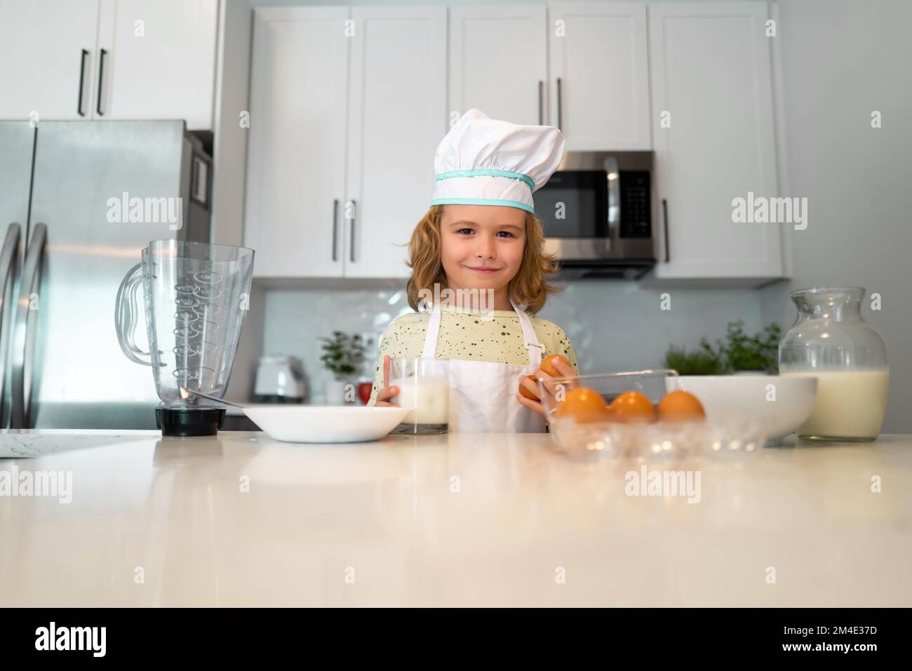 Chef kid boy baking on the kitchen. Child chef cook prepares food at ...