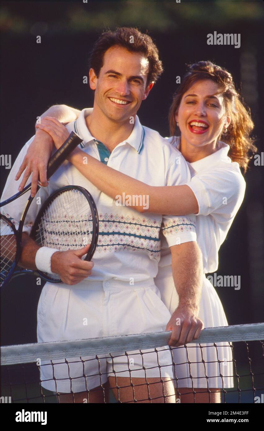 Younger couple embracing at a pause during a tennis game Stock Photo ...