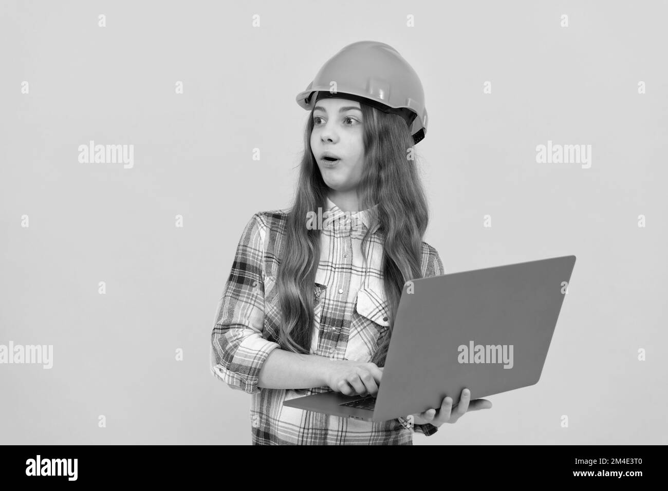 surprised teen girl in helmet and checkered shirt using computer ...