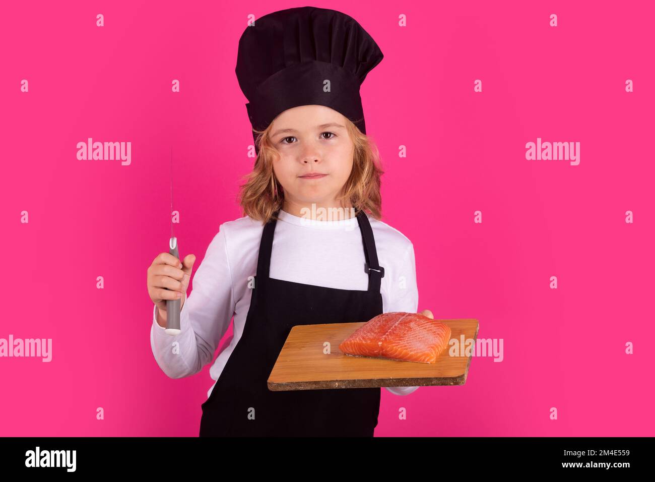 Kid cook hold cutting board with fish salmon steak and knife. Kid chef ...