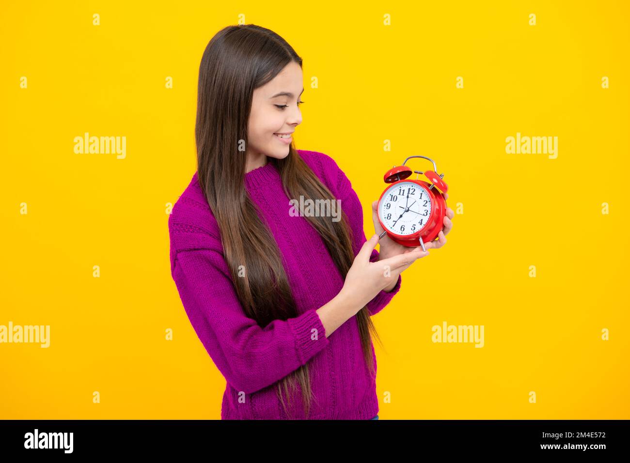 Teenager child hold clock isolated on yellow studio background ...