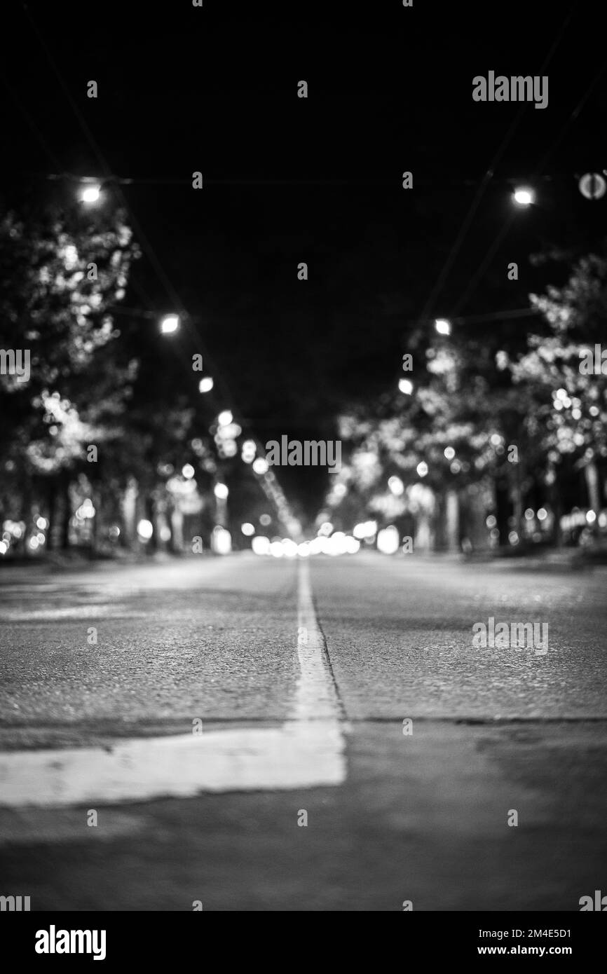 A vertical greyscale shot of a city street at night Stock Photo - Alamy