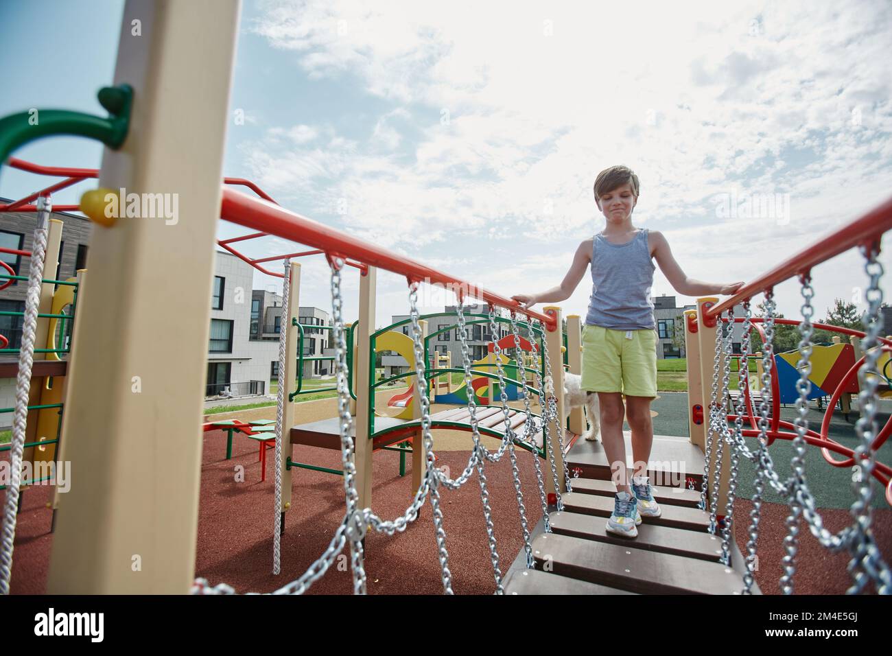 Full length portrait of young boy playing on colorful playground and ...