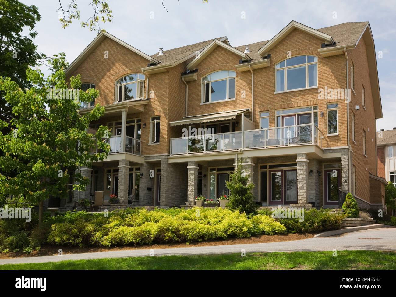 Two story tan brick condominium building with landscaped front yard in ...