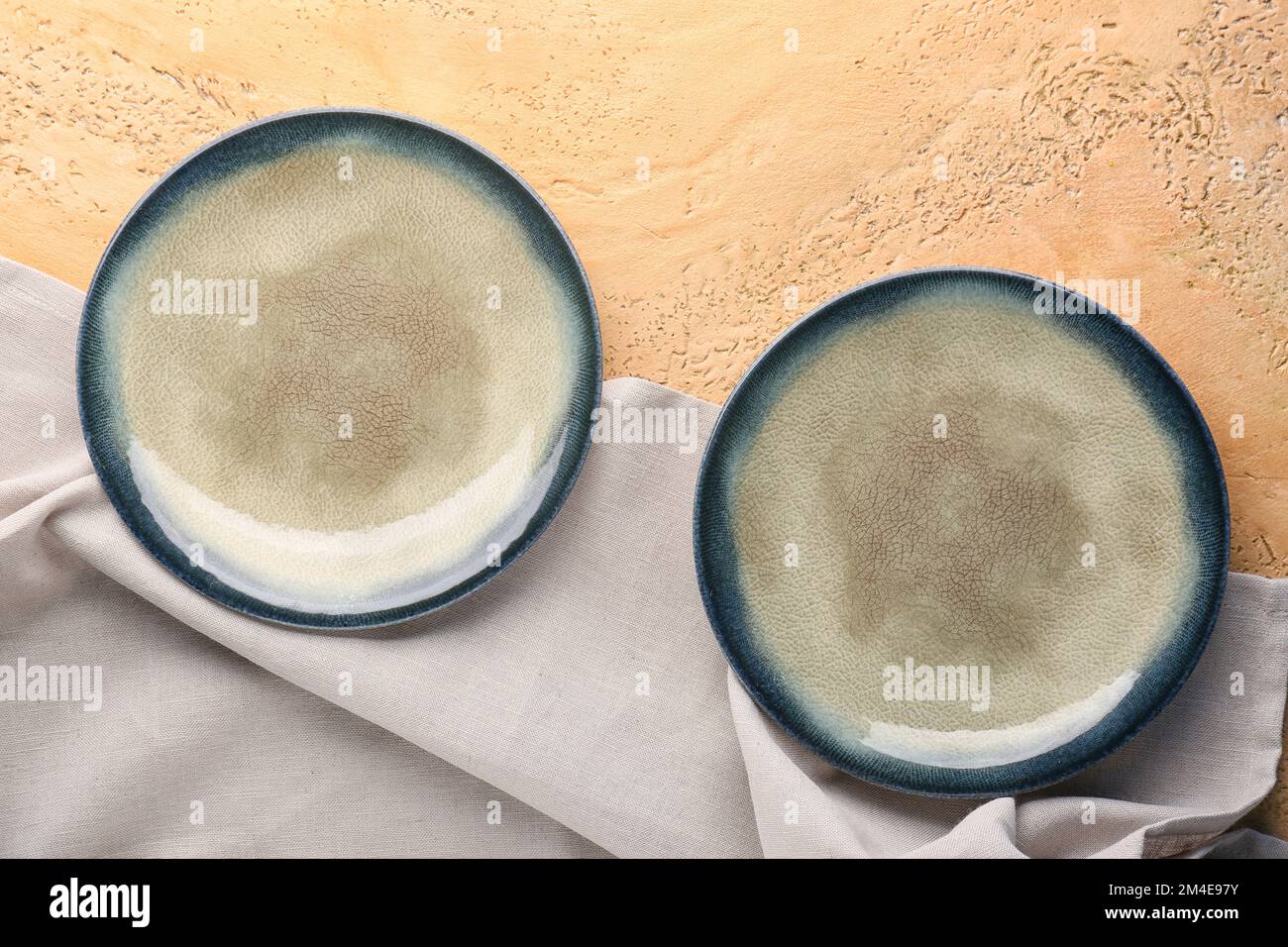 Stylish plates with grey napkin on beige grunge background Stock Photo ...