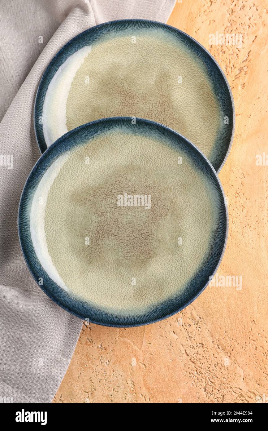 Stylish plates with grey napkin on beige grunge background Stock Photo ...