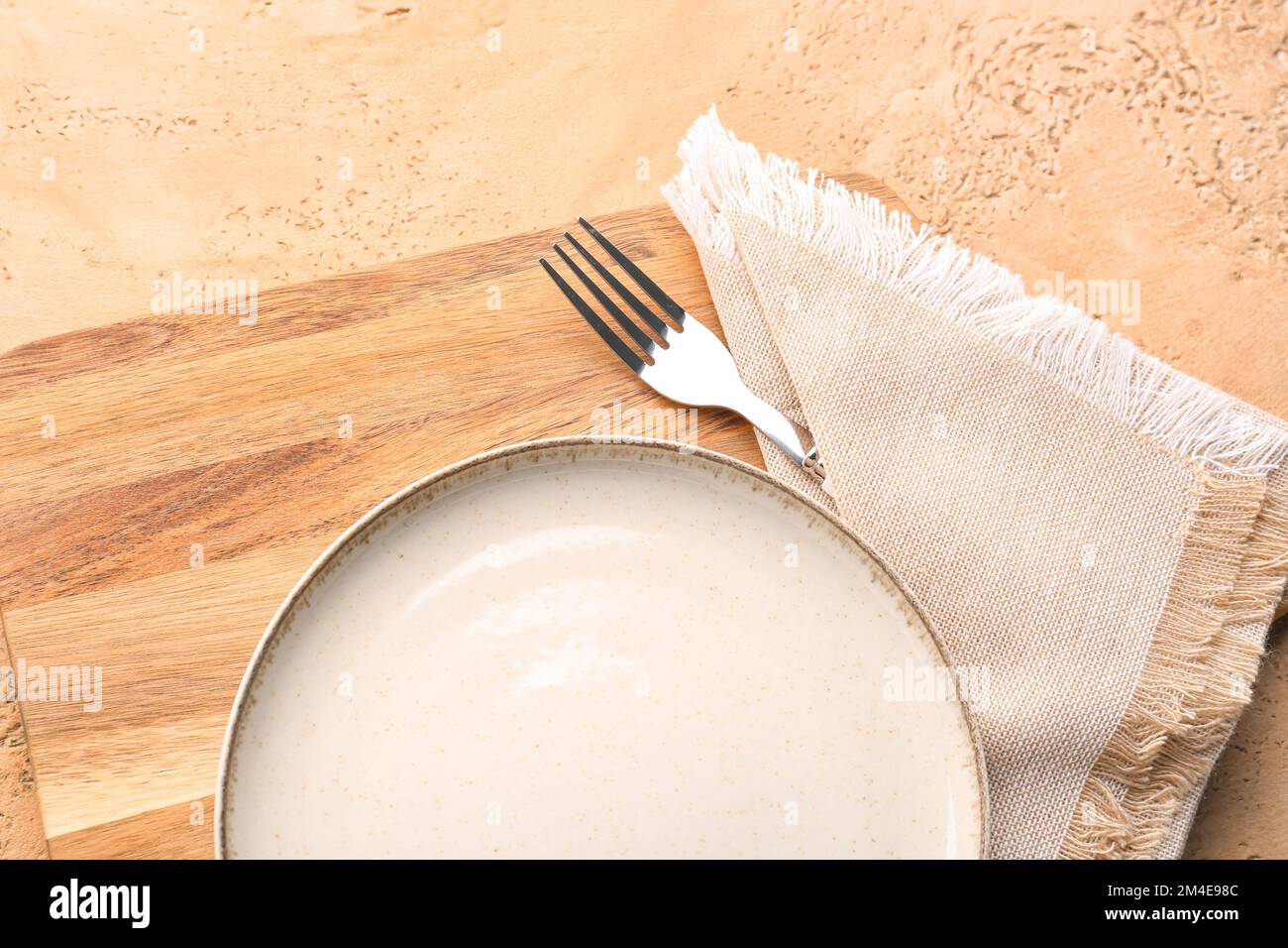 Wooden board with white plate, fork and napkin on grunge beige ...