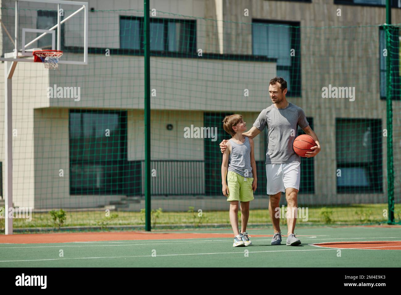 Full length portrait of happy father and son playing basketball ...