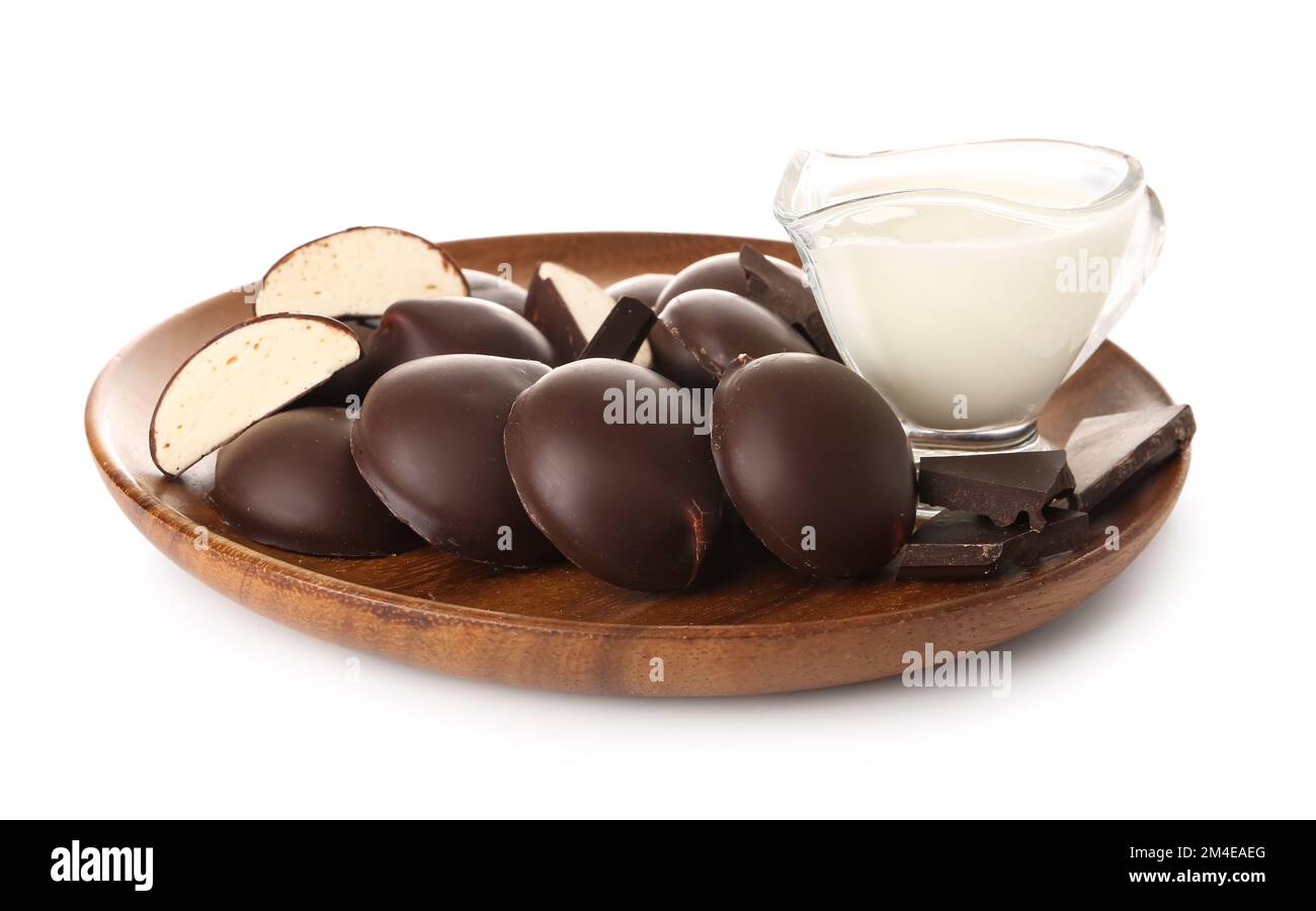 Wooden plate with sweet chocolate bird's milk candies and gravy boat of ...