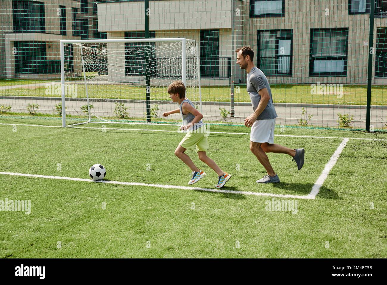 Side view portrait of father and son playing football together in ...