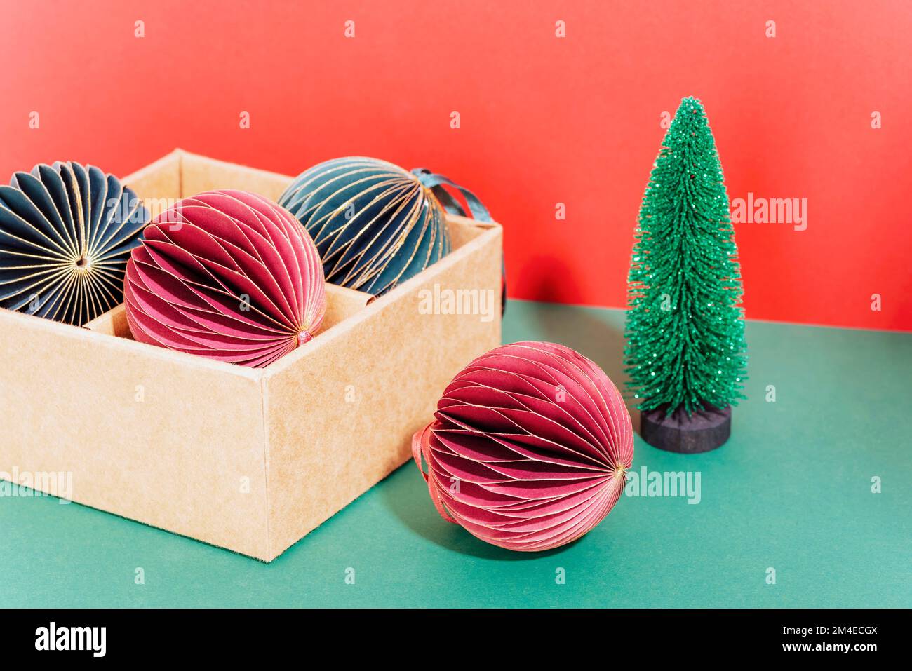 Christmas paper balls in a box and fir tree toy on red and green ...