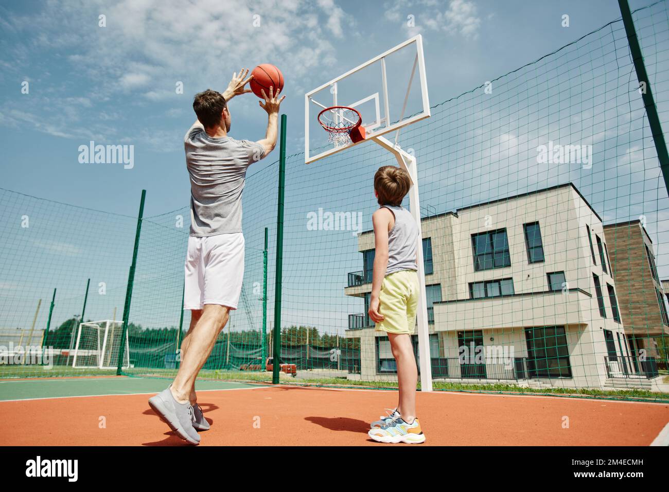 Wide angle portrait of father and son playing basketball together, man ...
