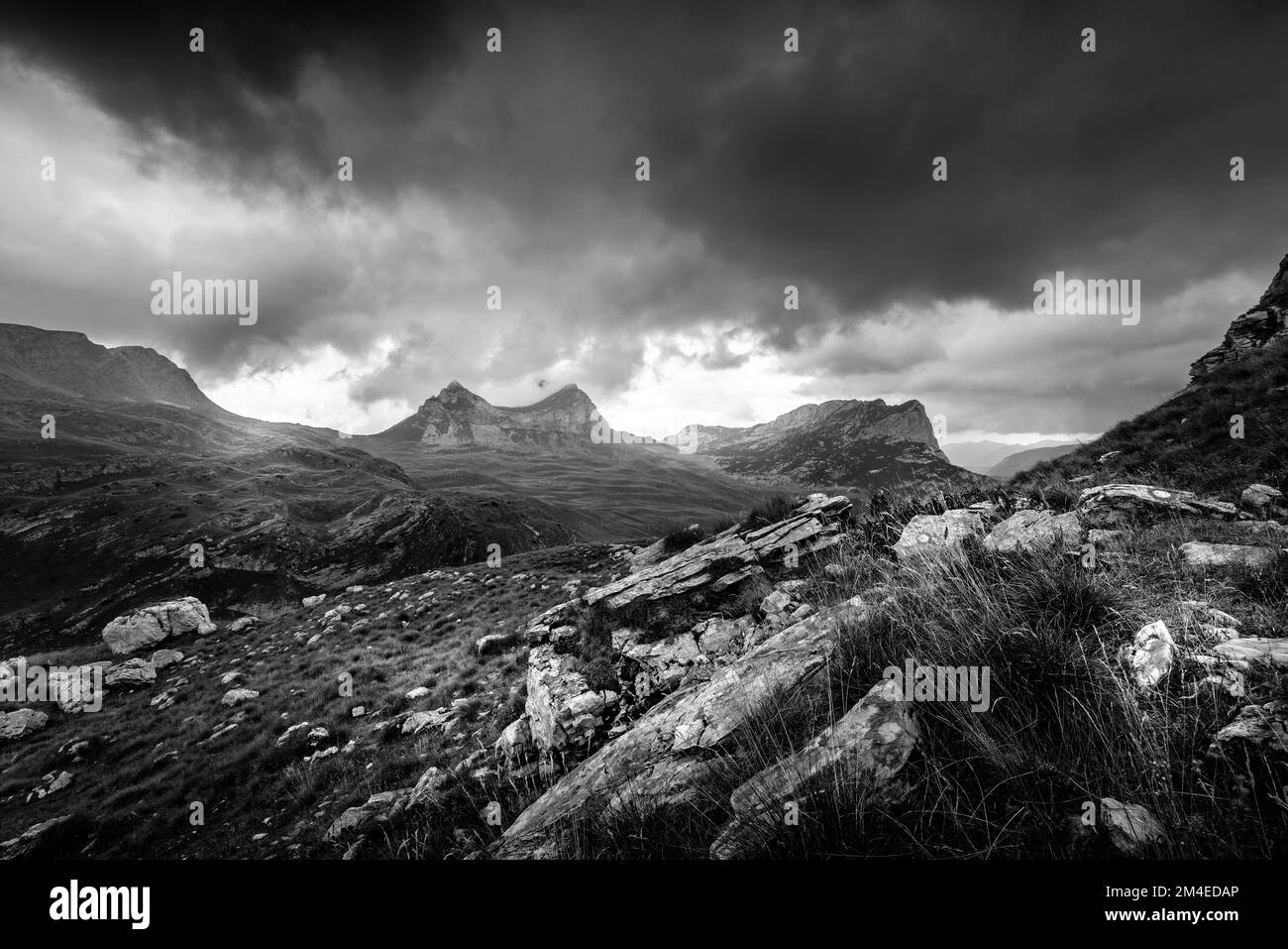 A scenic grayscale view of the landscape with mountains under a cloudy ...