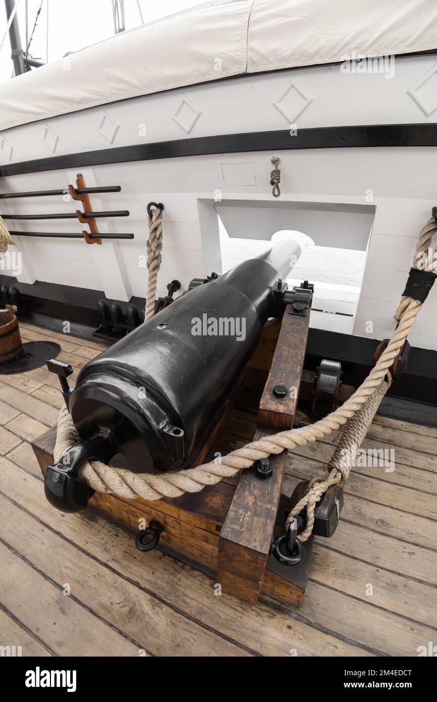 details of an old metal cannon with ropes on in a ship with a wooden ...
