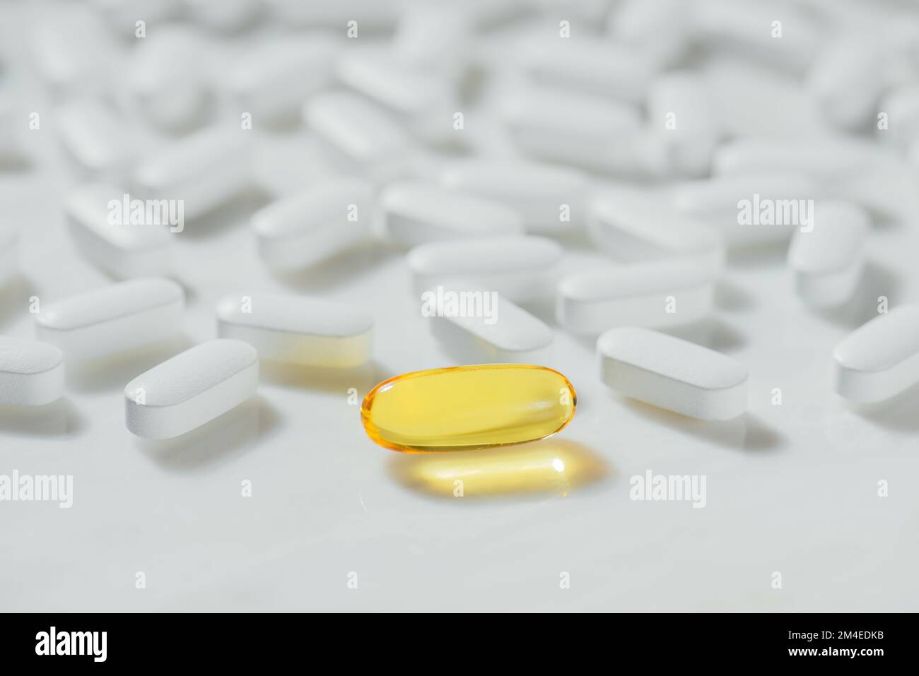 White tablets with a yellow gold capsule that stands out from the ...