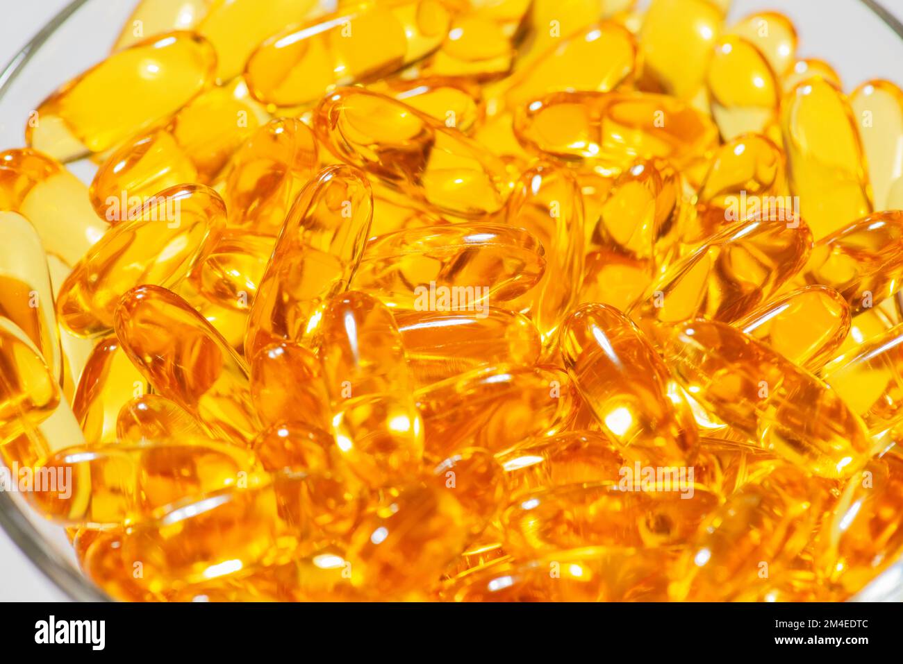 Omega-3 Fish oil capsules in a glass bowl on white marble background ...