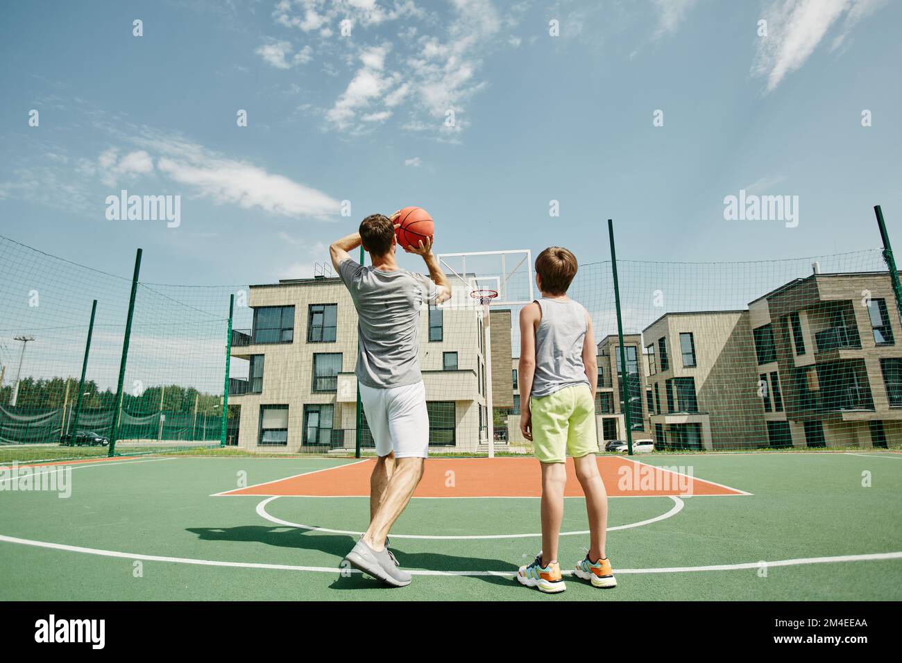 Wide angle motion shot of father and son playing basketball together ...