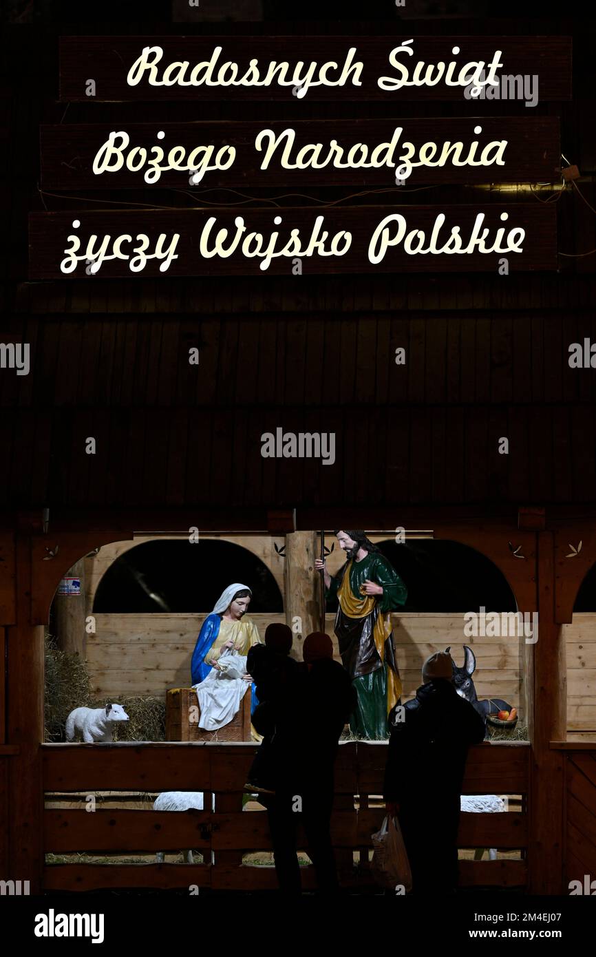 People are seen at a nativity scene with Christmas greetings by the ...
