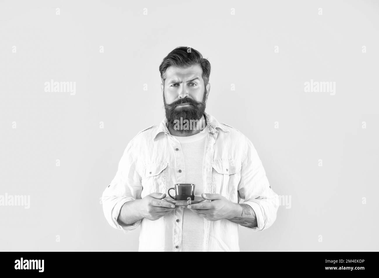 unhappy mature hipster with beard holding coffee cup on yellow ...