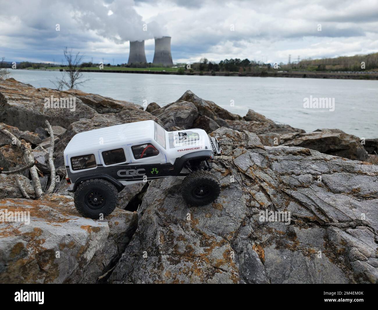 A toy car Jeep Wrangler on stones by the lake with a view of nuclear ...