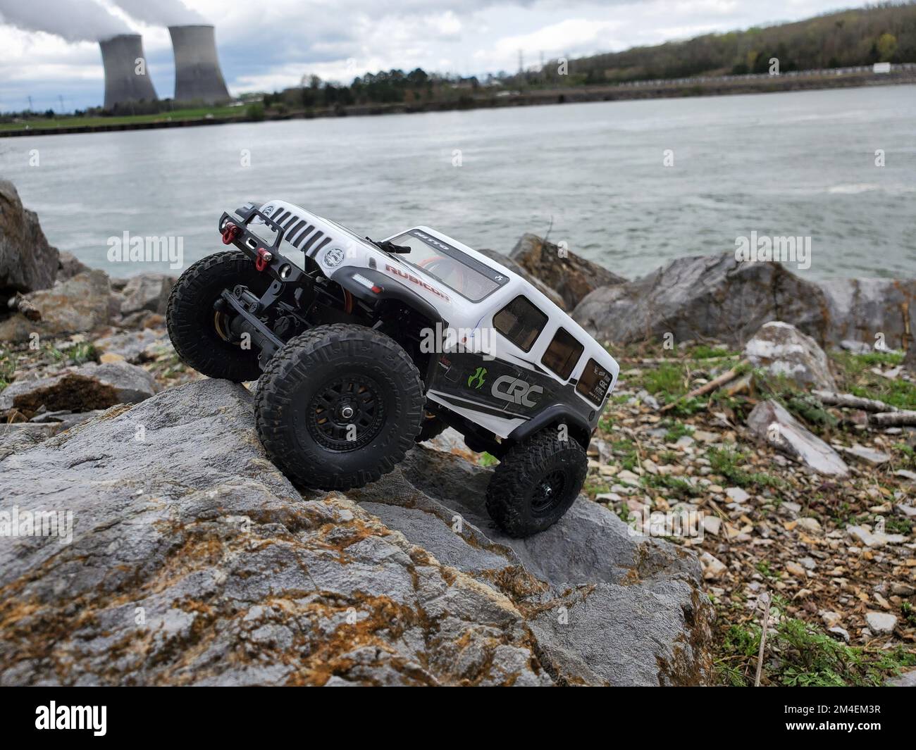 A toy car Jeep Wrangler on stones by the lake with a view of nuclear ...