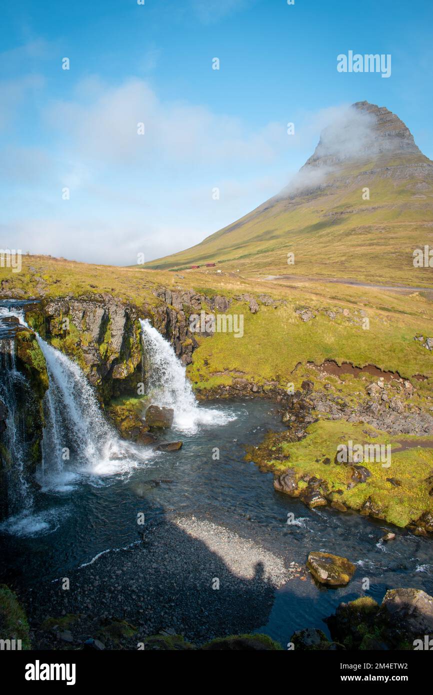 View of Kirkjufellsfoss at the base of Kirkjufell on a sunny day ...