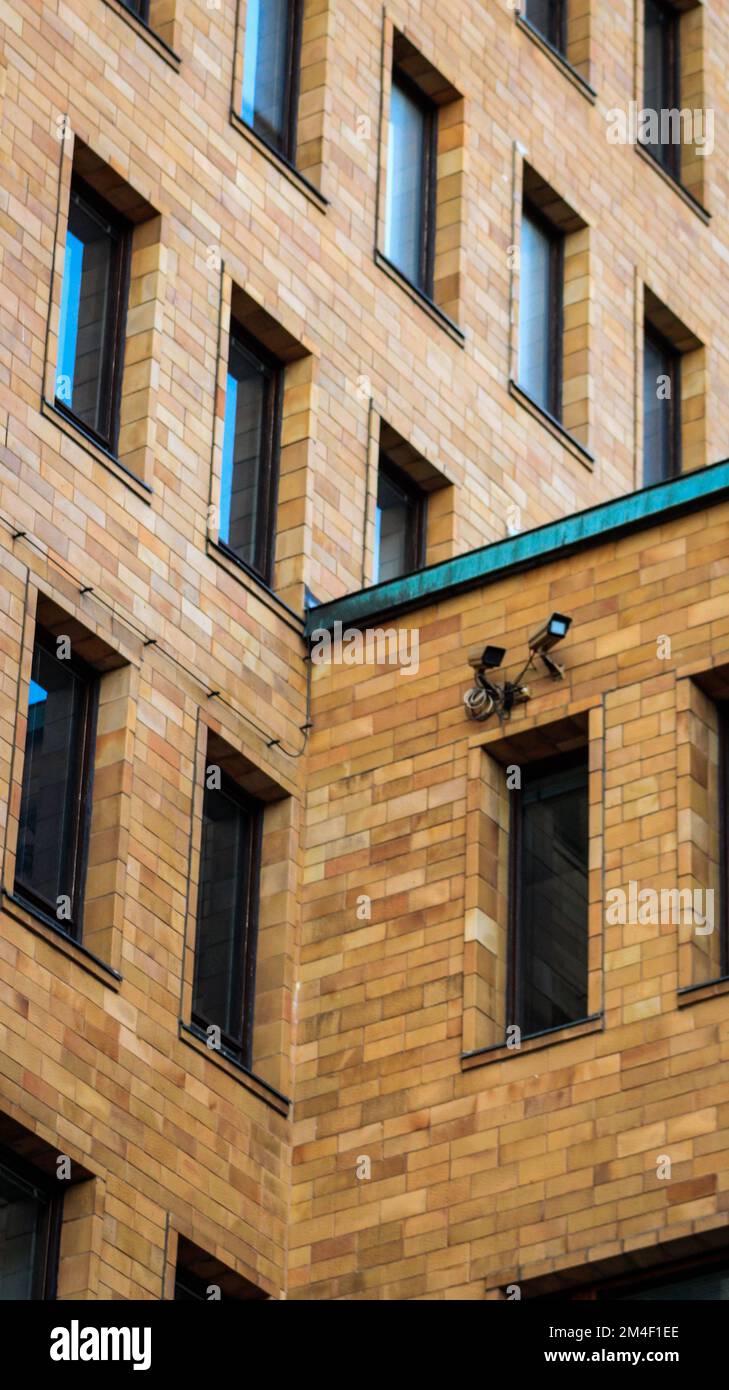 A vertical shot of brick-walled residential building with glass windows ...