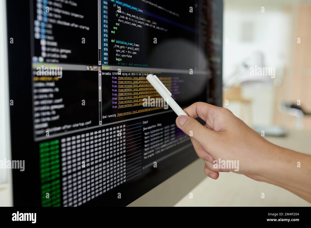 Hand with pen pointing at screen with programming code Stock Photo - Alamy