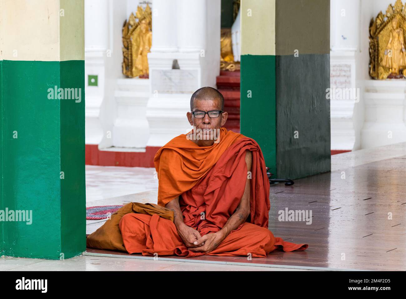A portrait of a Buddhist monk in tratizionell red robe siting on the ...