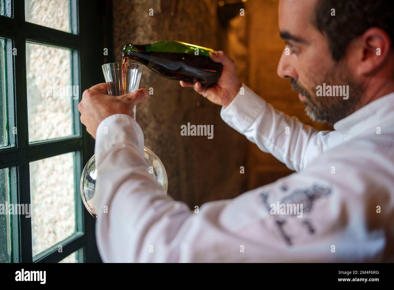 Sommelier decanting a bottle of red wine that was opened with hot tongs ...
