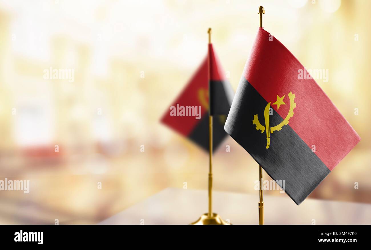 Small flags of the Angola on an abstract blurry background Stock Photo ...