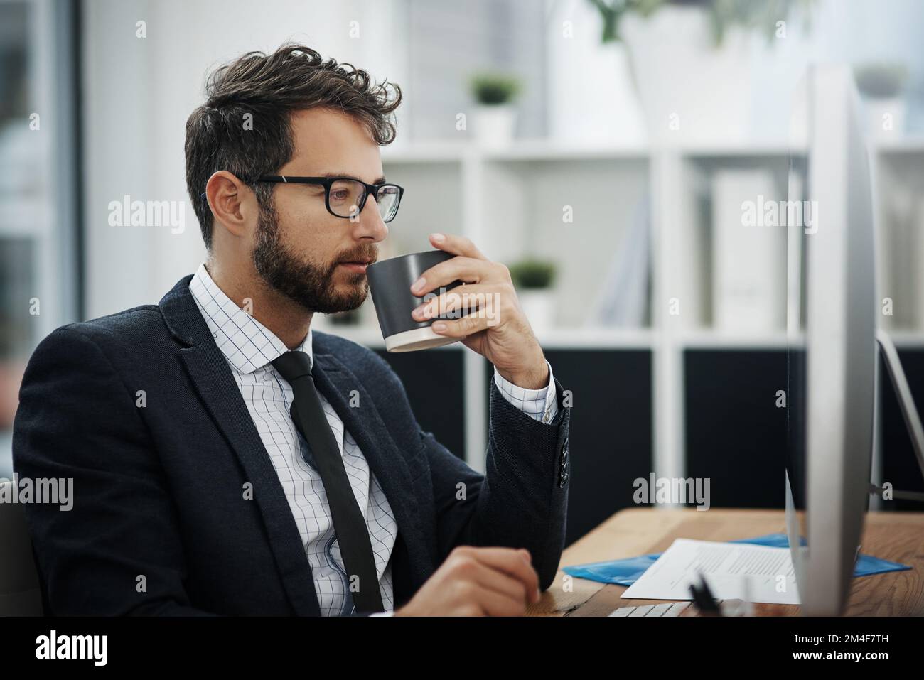 Coffee to keep his focus up. a young businessman drinking coffee while ...