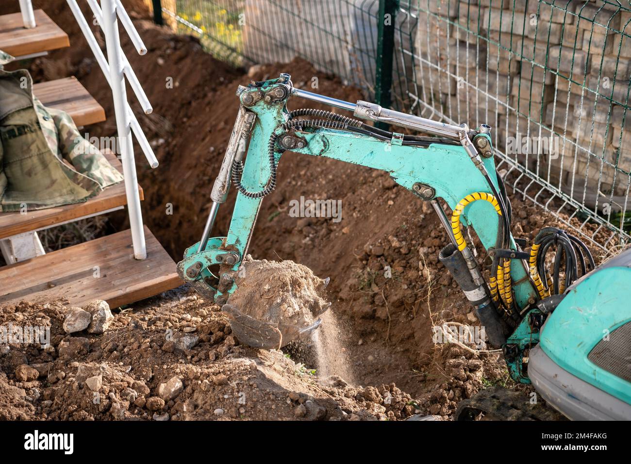 Mini excavator digs a trench to lay pipes. Close up of an excavator ...