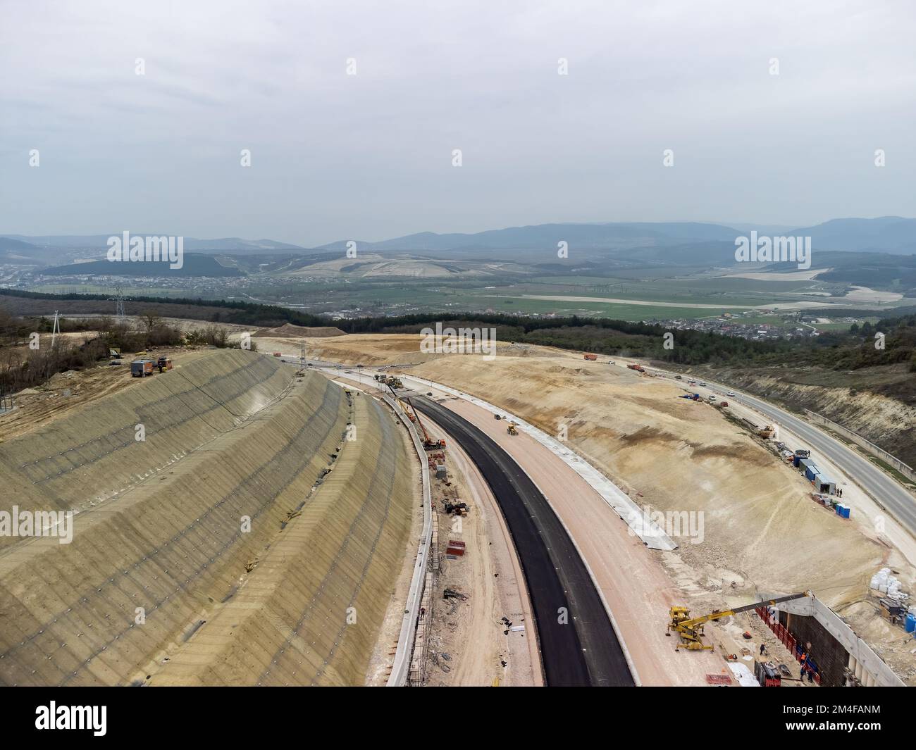 Mountain road constraction. Workers reinforce the slope over the new ...