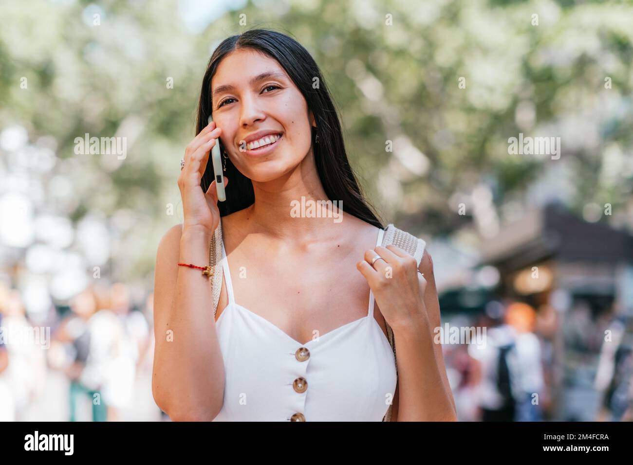 Happy Latin American female tourist with backpack smiling and looking away with smile while ...