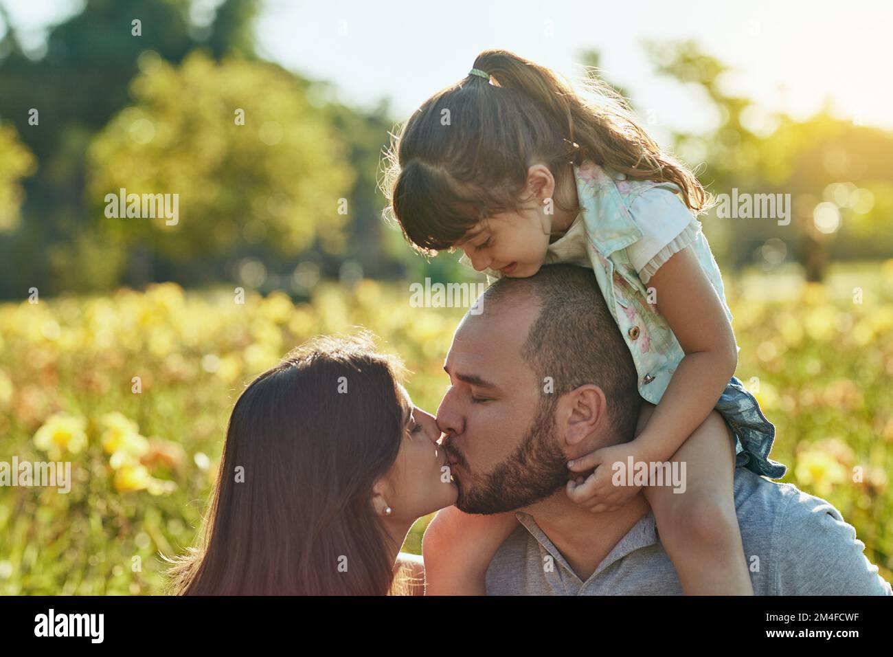 Family goals. an adorable little girl watching her parents kiss during ...