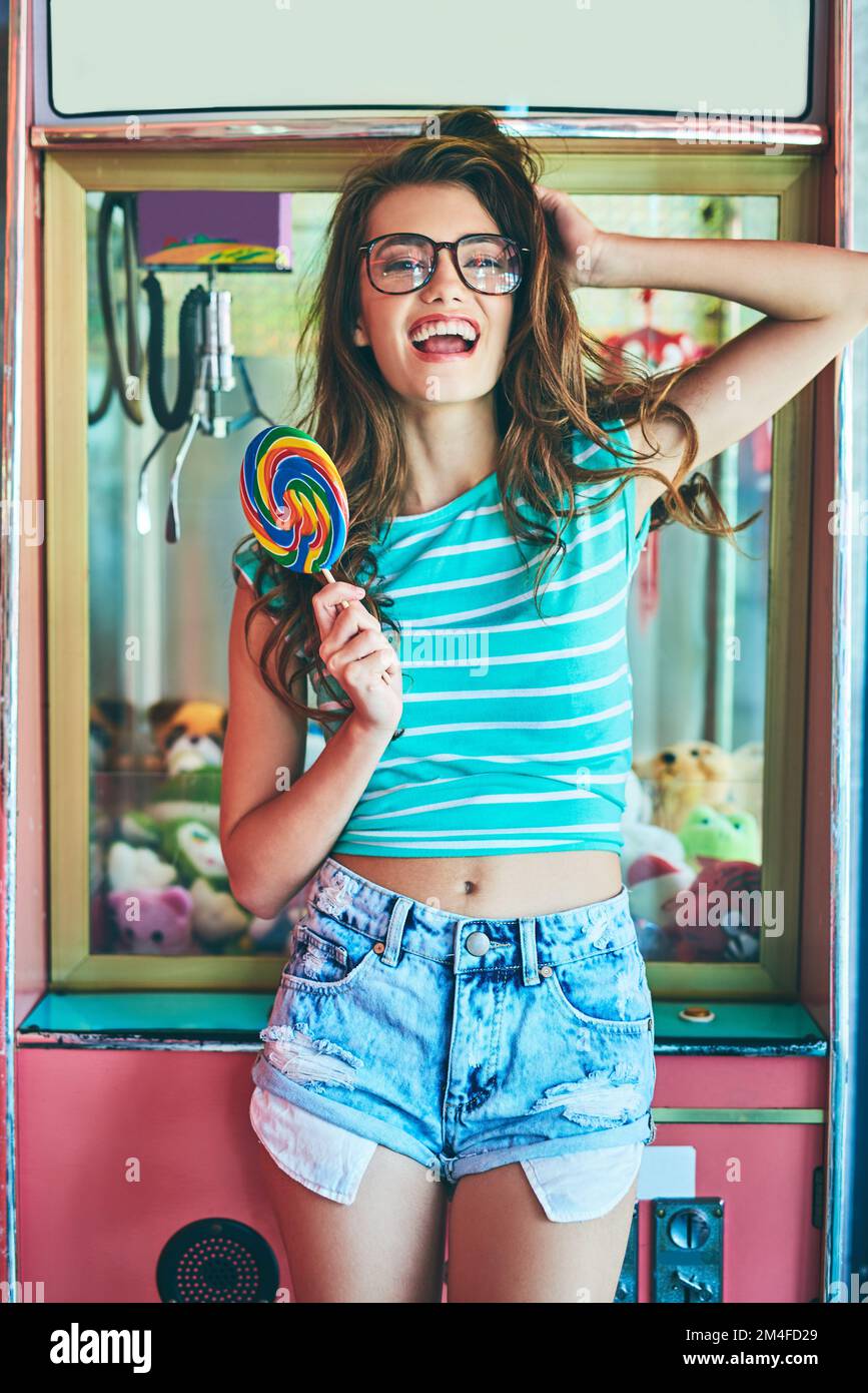 Fun and funky. Cropped portrait of an attractive young woman eating a giant lollipop in a retro ...