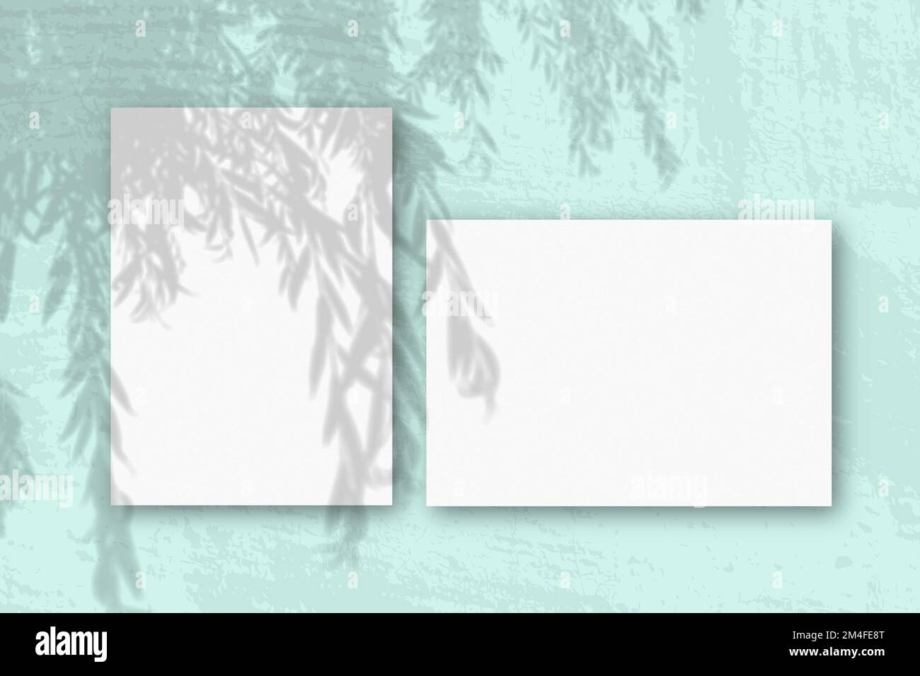 Horizontal and vertical sheets of white textured paper against a green ...