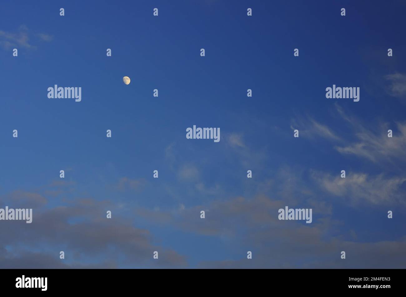 Real photo of the sky at dusk, light clouds and the moon. Focus around ...